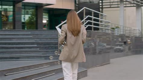 Classically Dressed Businesswoman Climbs The Stairs Of A Modern