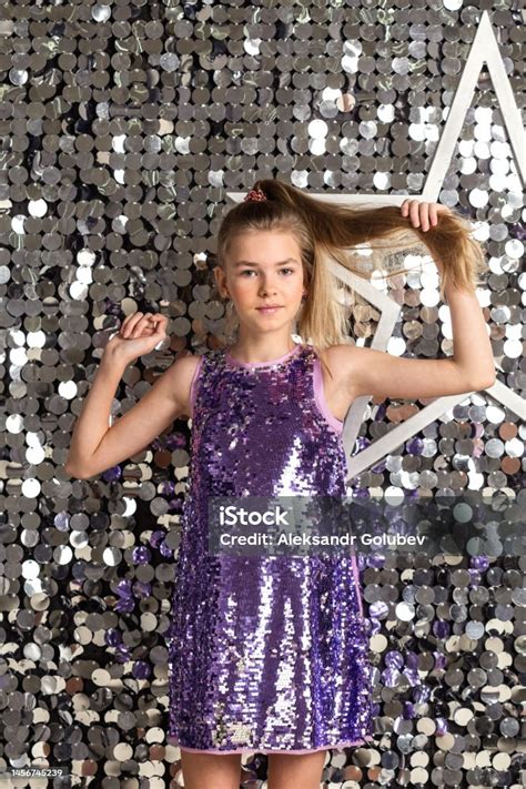 디스코 드레스를 입은 십대 커버 소녀가 별과 함께 밝은 배경에서 포즈를 취하고 카메라를 바라보고 있다 은색 옷을 입은 헤어스타일을 가진 예쁜 파티 소녀 복고풍 음악 스타일