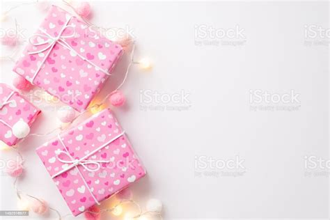 발렌타인 데이 개념입니다 하트 패턴 전구 화환과 빈 공간이 있는 격리된 흰색 배경에 푹신한 퐁퐁이 있는 포장지에 분홍색 선물