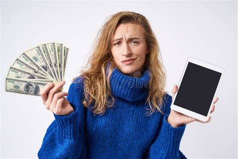 Неудовлетворенная курчавая белокурая женщина с планшетом и деньгами в