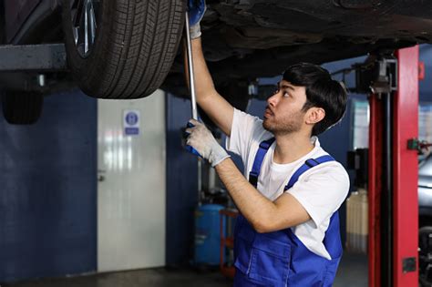 남자 기술자 자동차 정비사는 제복을 입고 수리 차고 역에서 리프트 자동차 서비스를 점검하거나 유지 보수합니다 렌치를 잡고 고장 차량을 고정하는 작업자 자동차 센터 수리
