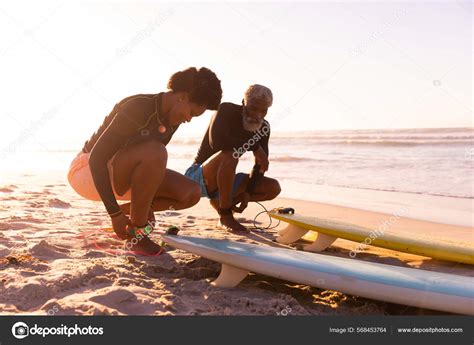 African American Couple Tying Surfboards Strings Ankles Beach Clear Sky