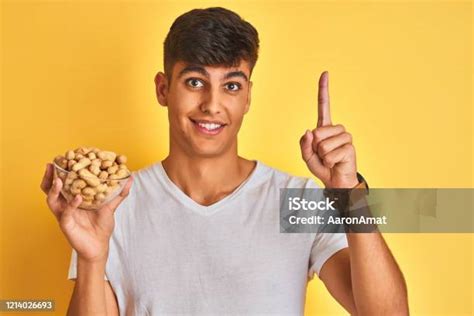 젊은 인도 남자 보유 그릇 위에 고립 된 노란색 배경 에 놀란 아이디어 또는 질문 가리키는 손가락 으로 행복한 얼굴 번호 하나 가리키기에 대한 스톡 사진 및 기타 이미지