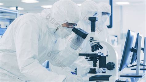 在实验室穿着防护服的科学家利用显微镜进行图片 包图网企业站