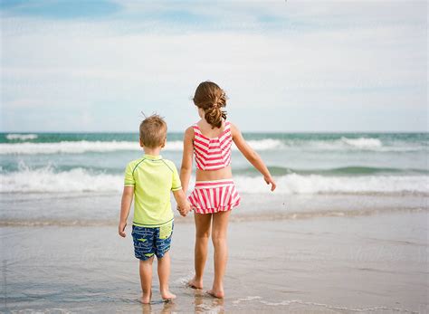 Big Sister Holding Little Brothers Hand While Walking Towards The