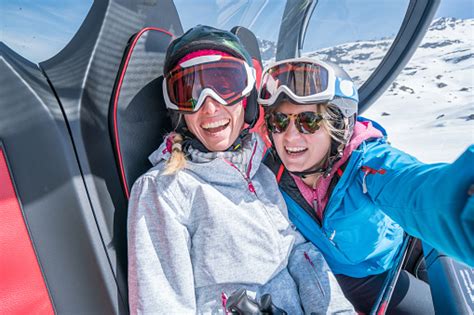 스위스에서 스키 리프트에서 Selfie를 복용 하는 두 젊은 여성이 스키 두 여자 관광 스위스 알프스와 휴가 개념의 휴일 공중