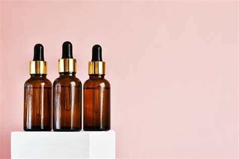 분홍색 배경에 흰색 연단에 파이펫이있는 갈색 유리 병에 천연 히알루론 세럼 복사 공간을 복사합니다 대체 의학 방향족 화장품 스킨