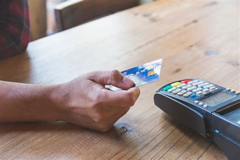신용 카드와 함께 손을 잡고 남자는 바 카운터에서 신용 카드 리더 기계와 신용 카드를 들고 Nfc 기술로 비접촉식 신용 카드로 지불 하는 고객의 손 카드 여가활동 게임에