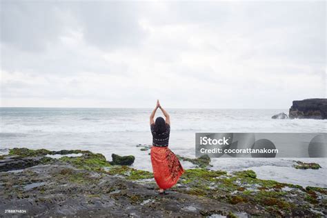 발리 원주민 사롱을 입고 요가를 하는 아시아 여성이 인도네시아 발리 섬의 인도양 해안에서 포즈를 취하고 있다 여행 목적지 그리고 아시아 컨셉의 자유 생활 35 39세에 대한