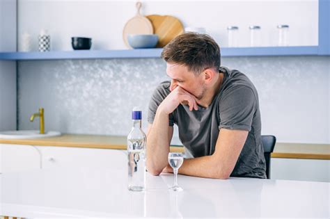 보드카 한 병을 들고 집에 혼자 앉아 우울한 삶에 대해 생각하고 기분이 좋지 않으며 길을 잃고 불행하고 지친 청년에 대해 알코올 중독과 나쁜 습관 개념 술 마실 것에 대한