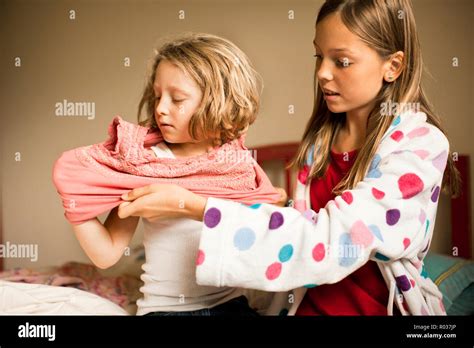 Big Sister Helping Her Little Sister Get Dressed In The Morning Stock