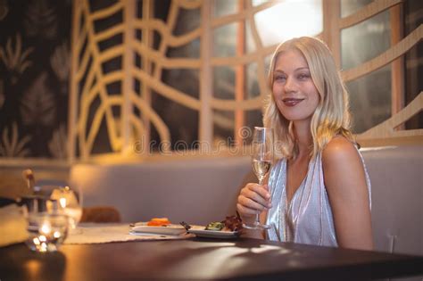 Woman Sitting In Restaurant Booth Holding Champagne Flute With Salad