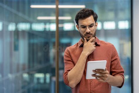 Thoughtful Programmer With Tablet In Modern Office Setting Analyzing Code And Contemplating