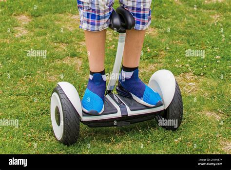 The Feet Of A Boy In Sneakers Stand On A Hoverboard Close Up Against