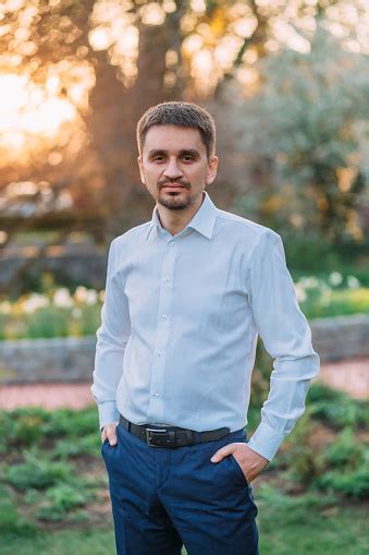 강 모와 짧은 헤어 스타일과 갈색 머리 남자의 초상화입니다 잔인 한 수염 블루 팬츠와 셔츠 석양의 백라이트에 있는 세련 된 남자