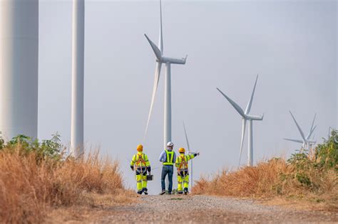 엔지니어 측량사 및 관리자가 유니폼을 입고 보행 상자 검사 및 태블릿을 착용하고 풍력 터빈 농장에서 전기로 순환 청정 전력 에너지 개념을위한 대체 재생 가능 에너지로