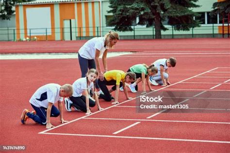여성 코치 훈련 운동 선수 경기장에서 러닝 머신에서 달리는 어린이 그룹 스포츠 업적 공부 목표 기술의 개념 어린 소년과 소녀는 야외에서 훈련합니다 교습에 대한 스톡 사진 및