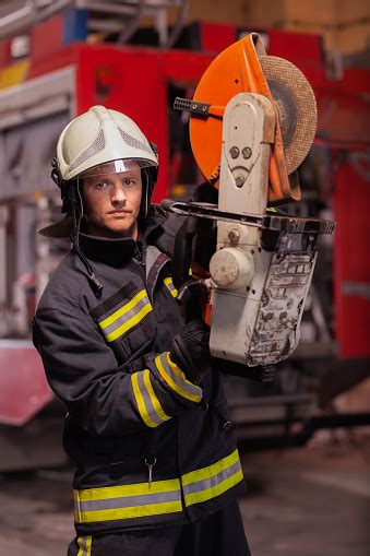 제복을 입은 전문 소방관은 보호 헬멧을 착용하고 응급 구조 장비를 착용하고 서 있습니다 원형 유압 절단 하드 공구 백그라운드에서 소방차 구조에 대한 스톡 사진 및 기타