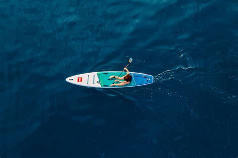 2022년 6월 21일 달라만 터키 바다에서 패들 보드를 타고 있는 여성의 공중 보기 바다에서 빨간 외륜 수프 보드를 타고 노를