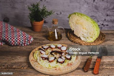 말린 문어 다리는 나무 접시에 갈가리 찢긴 양배추 잎 칼 붙이가있는 소박한 테이블 양배추 조각 및 기름 통 클로즈업에 조각으로