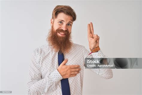 가슴과 손가락에 손을 들고 맹세하고 충성약속 맹세를 하는 고립된 흰색 배경 위에 서있는 젊은 빨간 머리 아일랜드 사업가 경영자에 대한 스톡 사진 및 기타 이미지 Istock