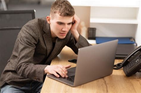 Premium Photo Young Cheerful Programmer Working In Office On Laptop