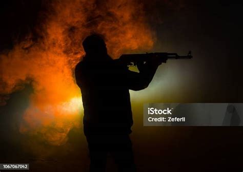소총 어두운 톤된 안개 배경 또는 검은 발라 클 라바 손에 들고 총 입고 위험한 산적에 공격을 준비와 남자의 실루엣 테러 무기 테마 장식으로 촬영 Ak 47 소총에 대한