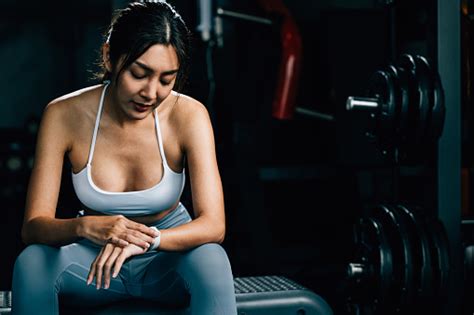 체육관 인테리어에서 운동 한 후 벤치에서 쉬고 모든 업데이트를 확인하는 아시아 여성 남자 피트니스 체육관 센터에서 훈련 중 스마트 시계를 사용하는 여성 스포츠 운동 건강한