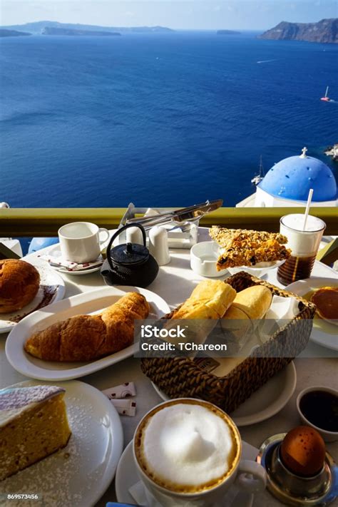 아름 다운 푸른 바다 보기와 아 교회 카푸치노 케이크 빵 삶은 계란 뜨거운 차 팬케이크와 시리얼 바와 흰색 대리석 테이블에 찬 크로 포함 하 여 아침 식사를 즐길 수 아침