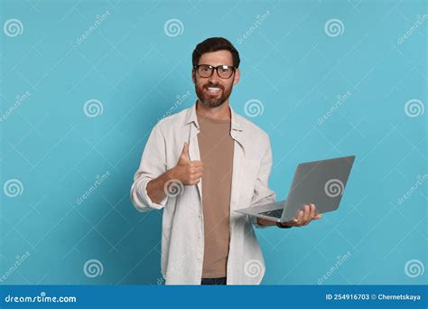 Man With Laptop Showing Thumb Up Gesture On Light Blue Background Stock