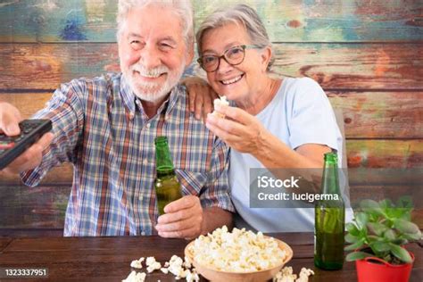 Tv에서 축구 경기를보고 맥주를 마시고 팝콘을 먹는 쾌활한 선임 부부 나무 배경 2명에 대한 스톡 사진 및 기타 이미지 2명 70 79세 Ale Istock