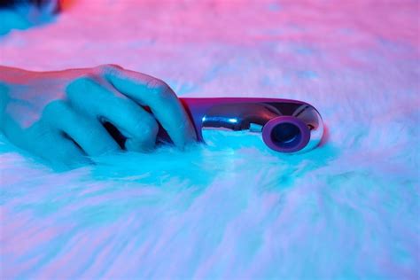 Conceito de desejo mulher deitada na cama segurando um vibrador vibrador na mão para se ajudar