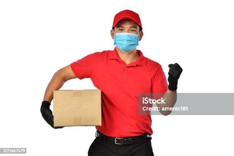 빨간 유니폼을 입은 행복한 젊은 아시아 배달 남자 의료 용 얼굴 마스크 보호 장갑은 흰색 배경에 고립 된 손에 골판지 상자를 들고 배달 남자는 소포 선적을 제공합니다 안전한