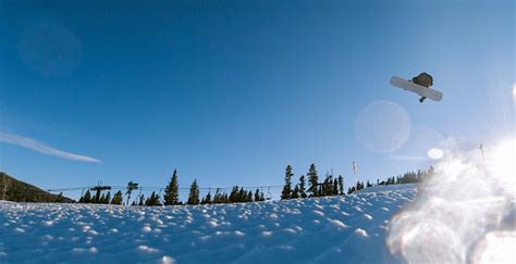 풀 윈터 기어의 스노우보더가 콜로라도 볼더 근처 엘도라 스키 리조트에서 숲과 스키 리프트를 배경으로 점프를 시도하며 화창한 날에 건강한 생활방식에 대한 스톡 사진 및 기타