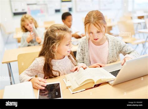 Two Girls In Elementary Babe Computer Class Learn Together On Laptop Stock Photo Alamy