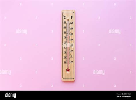 A Classic Wooden Thermometer On Pink Background Shows A High