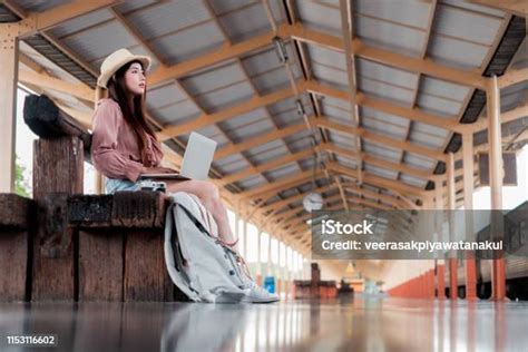 기차역에서 휴가 휴식을 계획하는 노트북을 사용하여 배낭을 가진 미소 하는 여자 여행자 휴식 개념 여행 개념n 가방에 대한 스톡