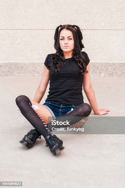 데님 반바지 콘크리트에 Siting와 카메라에 포즈를 취하는 갈색 머리를 가진 아름 다운 여자 갈색에 대한 스톡 사진 및 기타