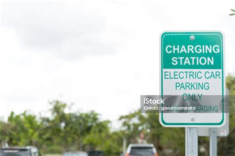 전자 차량 충전 스테이션은 부분적으로 흐린 하늘과 녹색 나무에 대한 기호 흰색과 청록색 색상 배경에 Ev 충전 스테이션 표지판