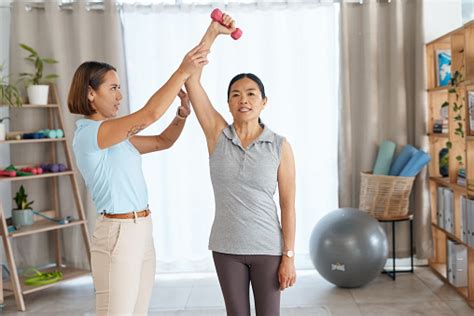 물리 치료 덤벨 운동 및 팔 회복 재활 또는 동작 훈련에 대한 지원을 받는 노인 아시아 노인 환자를 돕는 의료 물리 치료 및 물리 치료사 25 29세에 대한 스톡 사진 및