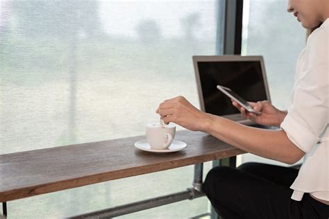 숟가락을 들고 그리고 커피숍 카페에서 노트북으로 나무 테이블과 사용 전화에 뜨거운 커피를 저 어 아시아 젊은 비즈니스 여자의 손