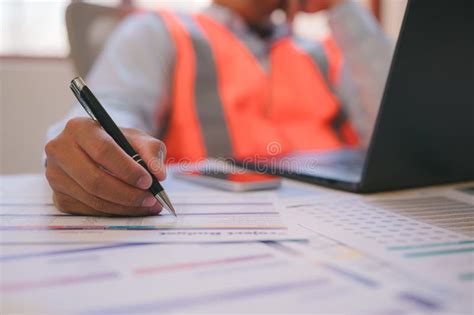 An Engineer Or Foreman Working On Site Sitting On Desk In Office Using Pen And Computer