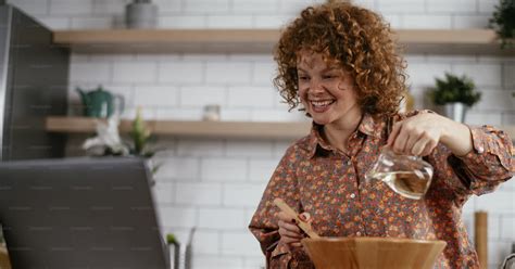 젊은 여자가 요리하는 동안 조리법을 읽고 있다 곱슬머리를 한 아름다운 여자가 부엌에서 즐기고 있다 사진 Unsplash의 초상 이미지