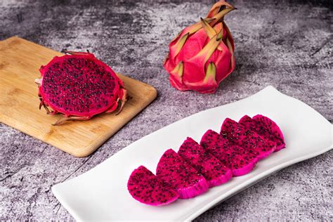 Pitaya 또는 용 과일 검은 씨앗으로 분홍색 내부를 드러내는 반 피타 하야와 먹을 준비가 된 과일 조각이있는 접시 클로즈업 0명에 대한 스톡 사진 및 기타 이미지