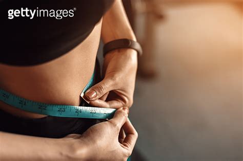 Athletic Slim Woman Measuring Her Waist By Measure Tape After Workout