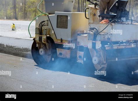 Construction Worker Uses An Asphalt Roller Compactor To Lay Asphalt On