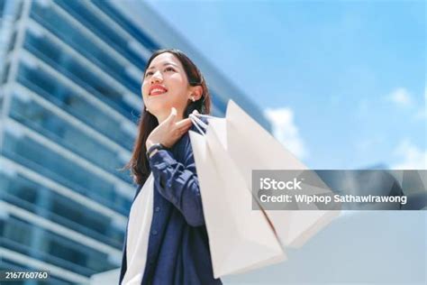쇼핑백을 들고 야외에 서있는 아시아 비즈니스 여성 푸른 하늘과 함께 도시 건물 배경 돈을 쓰는 라이프 스타일 쇼핑에 대한 스톡 사진 및 기타 이미지 Istock
