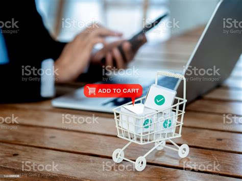 흰색 쇼핑 트롤리 카트에 추가 아이콘 기호는 스마트 휴대 전화와 노트북 컴퓨터 온라인 쇼핑 개념을 사용하는 비즈니스 사람 근처에 확인 표시가있는 소포 상자가 포함되어