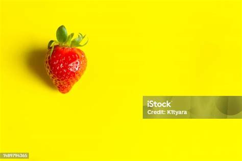 노란색 바탕에 녹색 꼬리가 있는 빨간 딸기 하나 밝은 노란색 배경과 빨간 딸기 딸기가 있는 여름 배경 0명에 대한 스톡 사진 및 기타 이미지 Istock