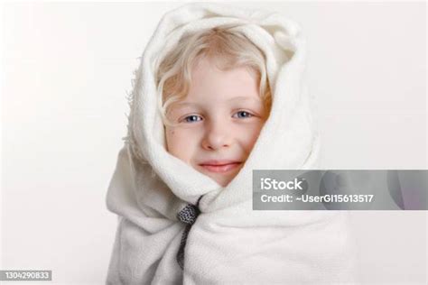 흰색 담요에 싸여 아름다운 미소 백인 소녀의 초상화 밝은 배경에 따뜻한 모직 목도리로 덮인 파란 눈을 가진 행복한 유치원 어린이